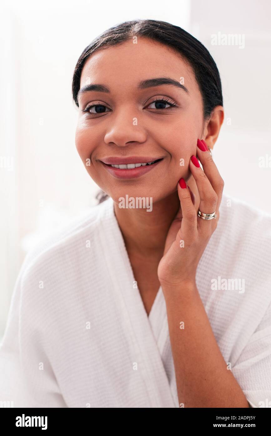 Pleased woman smiling and touching her cheek with one hand Stock Photo ...