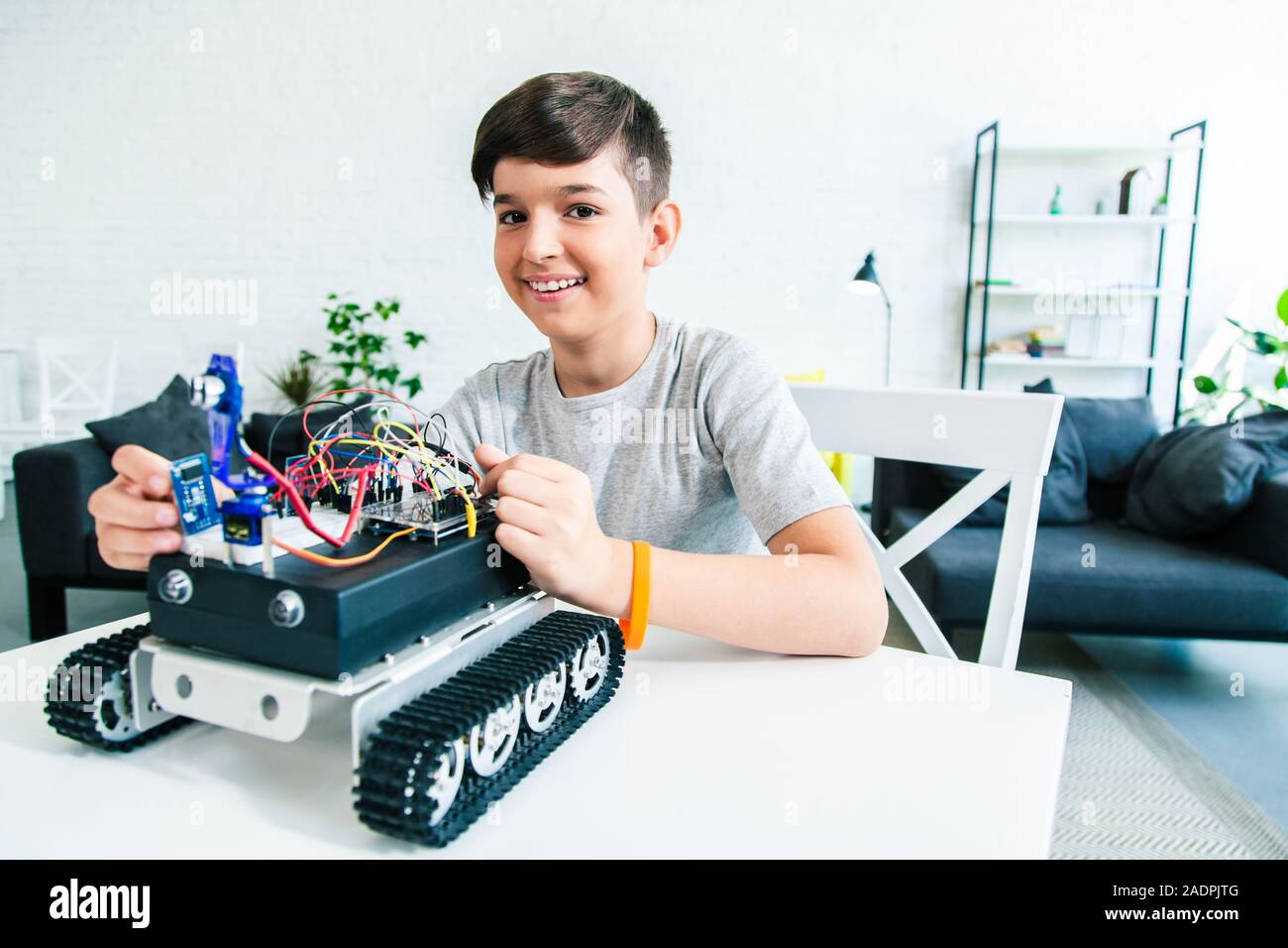 Smiling smart schoolboy constructing a modern robot Stock Photo - Alamy