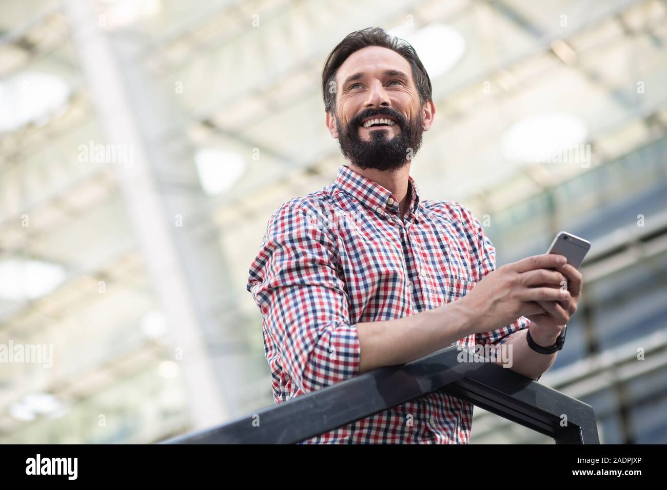 Low angle of a glad smiling man uisng his phone Stock Photo - Alamy