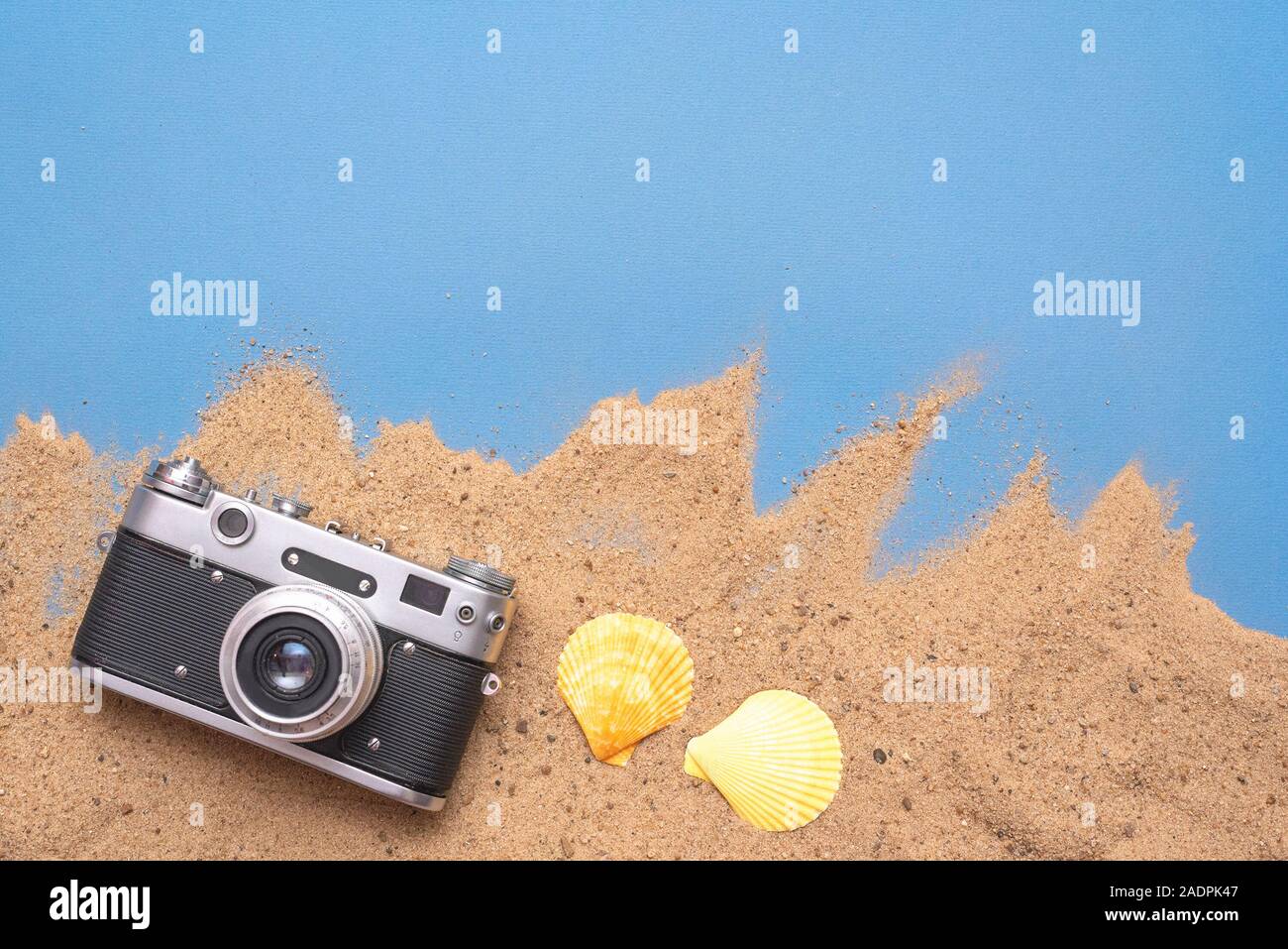 Sand beach, old photo camera and seashells on blue background with copy ...