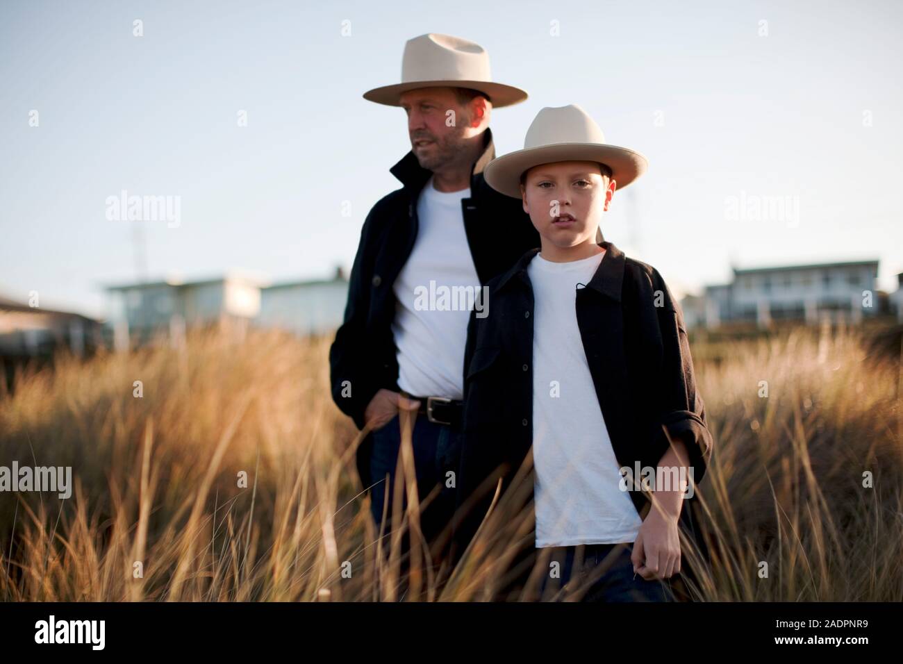 Father and son in cowboy outfits standing in tussock grass Stock Photo ...