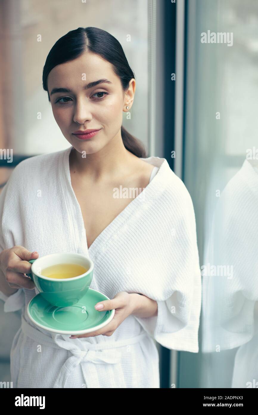 Waist up of thoughtful woman standing with cup of tea Stock Photo - Alamy