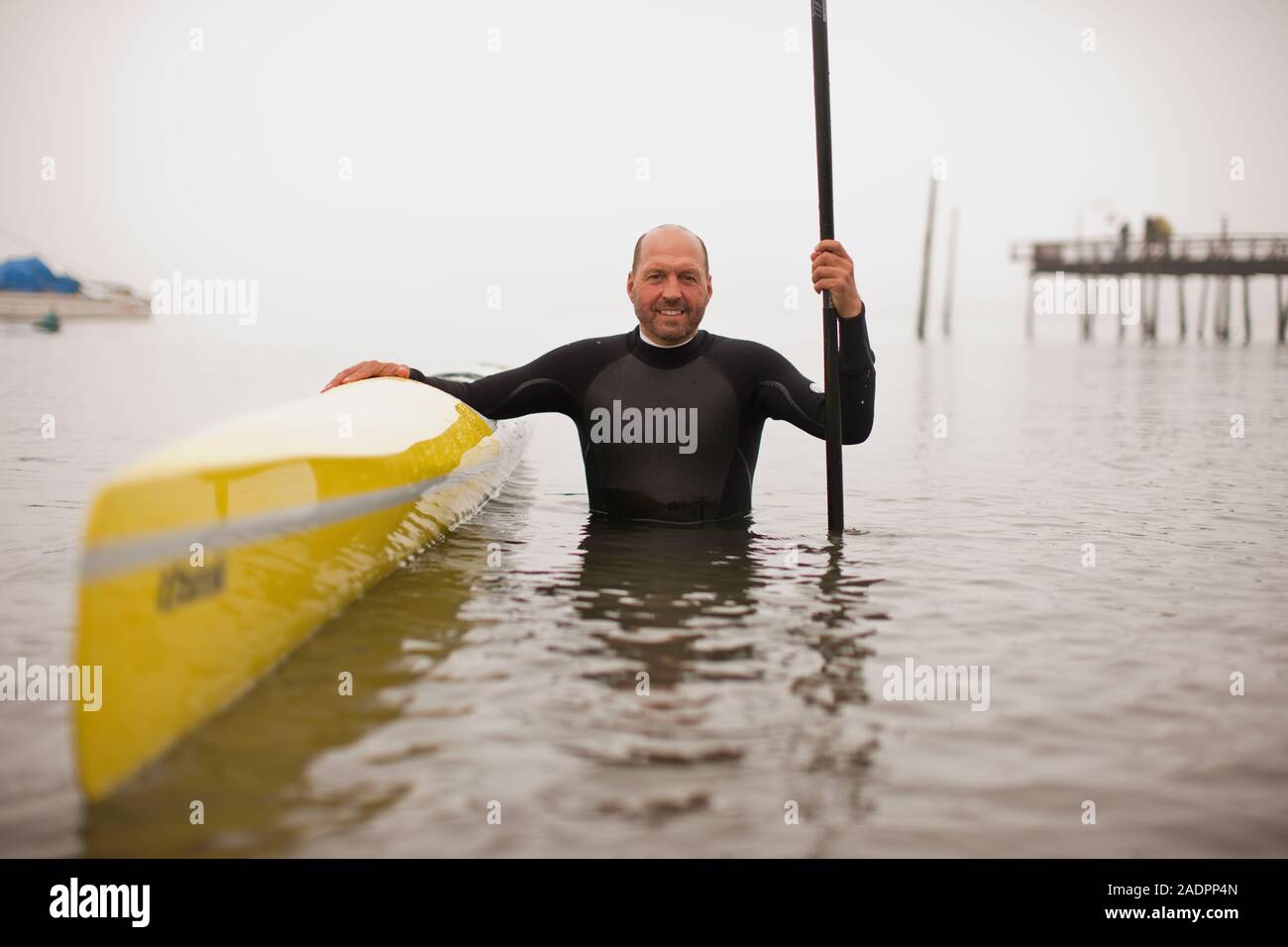 Male kayaker smiles as he poses with a kayak and an oar for a portrait ...