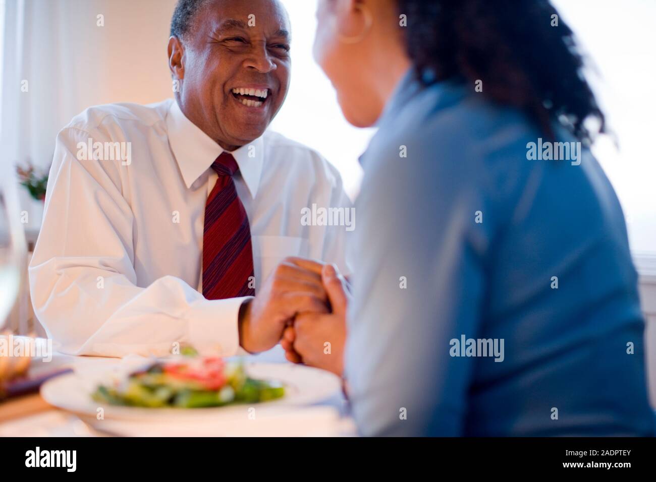 Couple holding hands over meal Stock Photo - Alamy