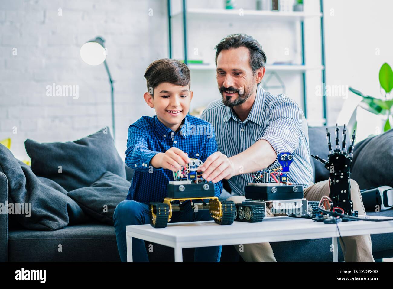 Overjoyed father helping his son with robot constructing Stock Photo ...