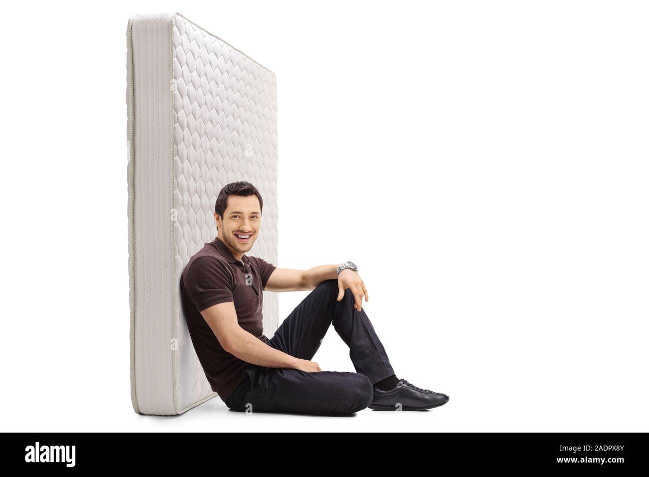 Young guy sitting on the floor and leaning against a bed mattress ...