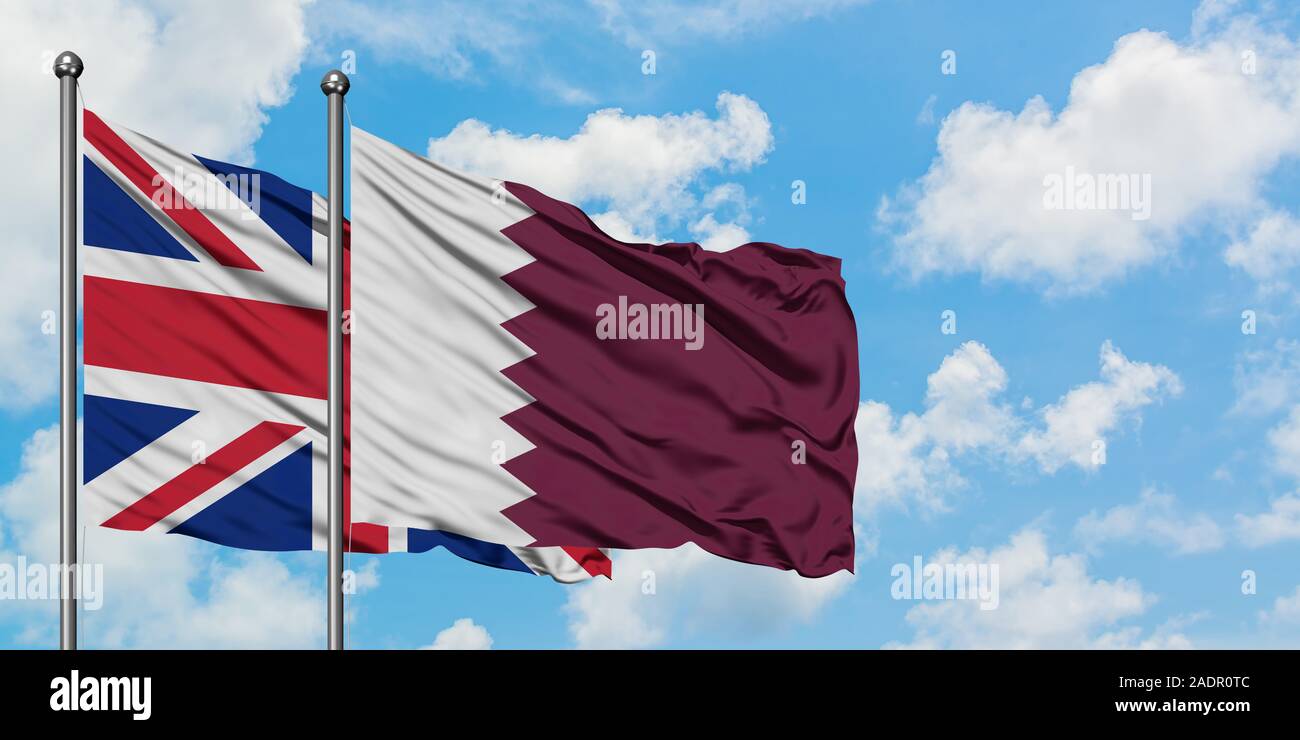United Kingdom and Qatar flag waving in the wind against white cloudy ...
