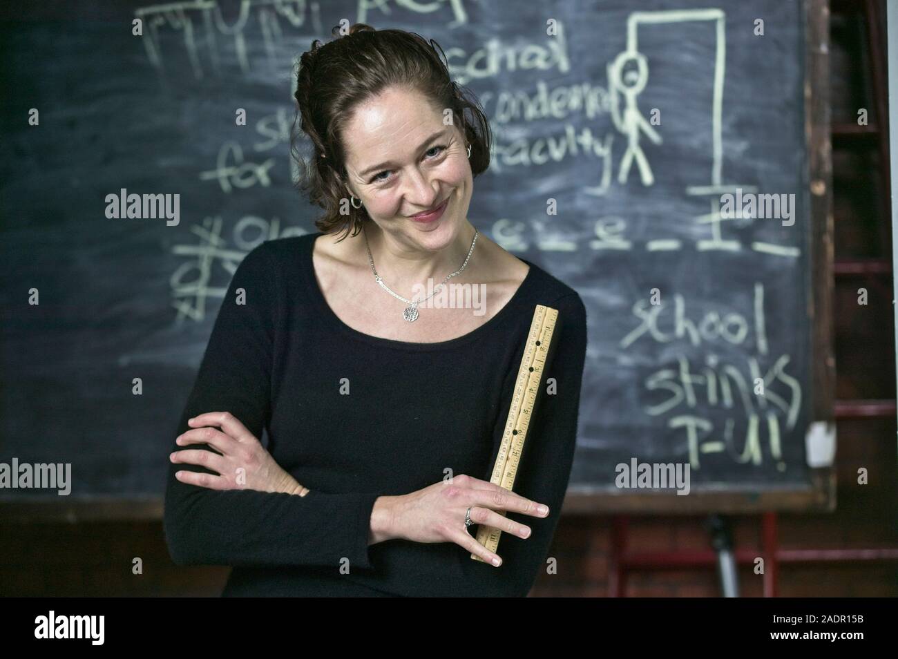 Portrait of a female classroom teacher holding a wooden ruler in front ...