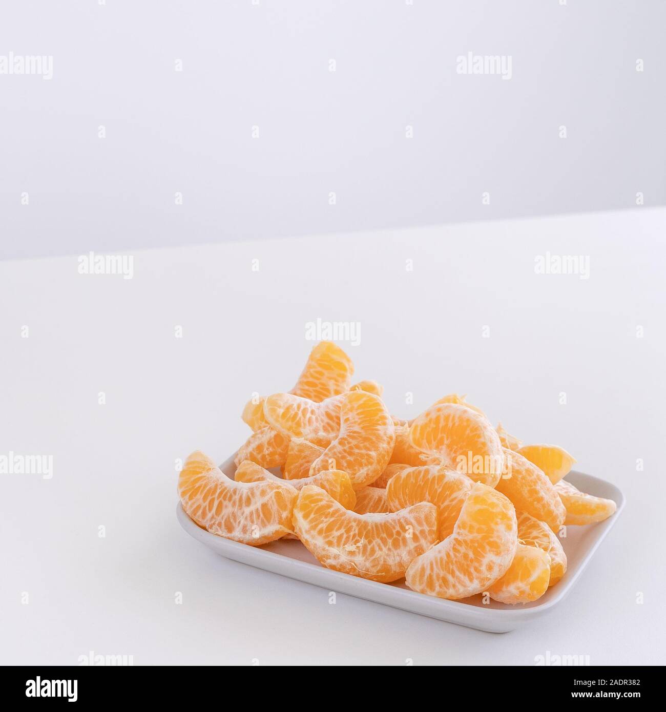 Beautiful peeled tangerines in a plate and metal basket isolated on ...