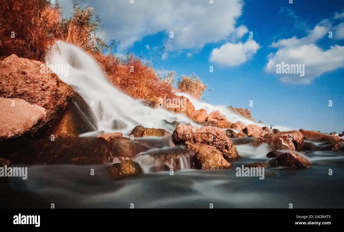 a fast waterfall near a quiet blue river Stock Photo - Alamy