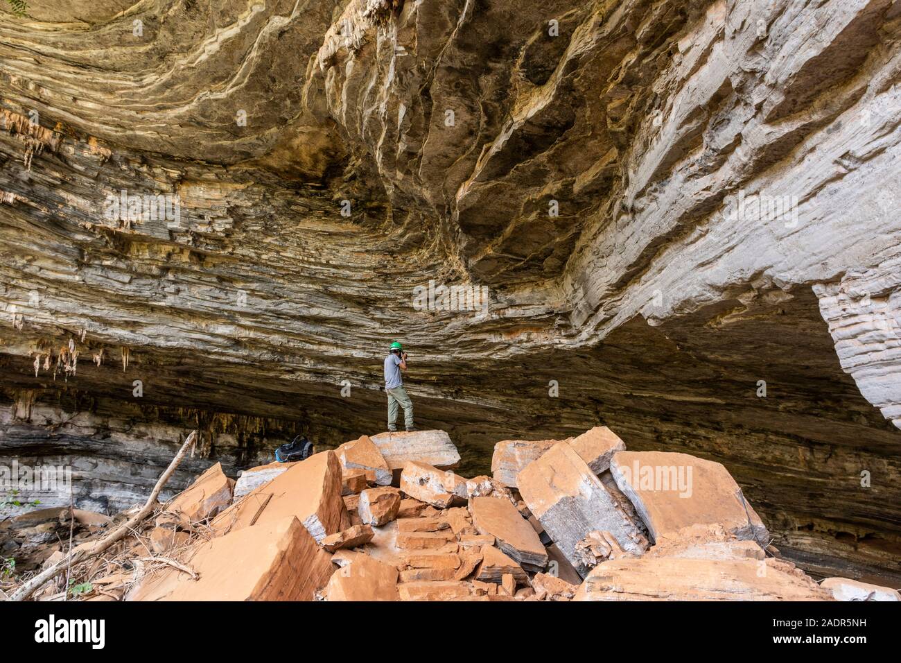 Photographer taking pictures at rocky cave entrance, Chapada Diamantina ...