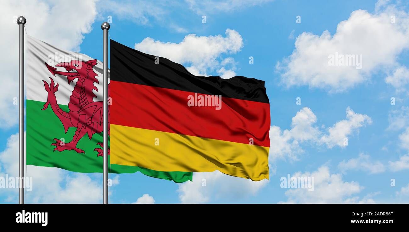Wales and Germany flag waving in the wind against white cloudy blue sky ...
