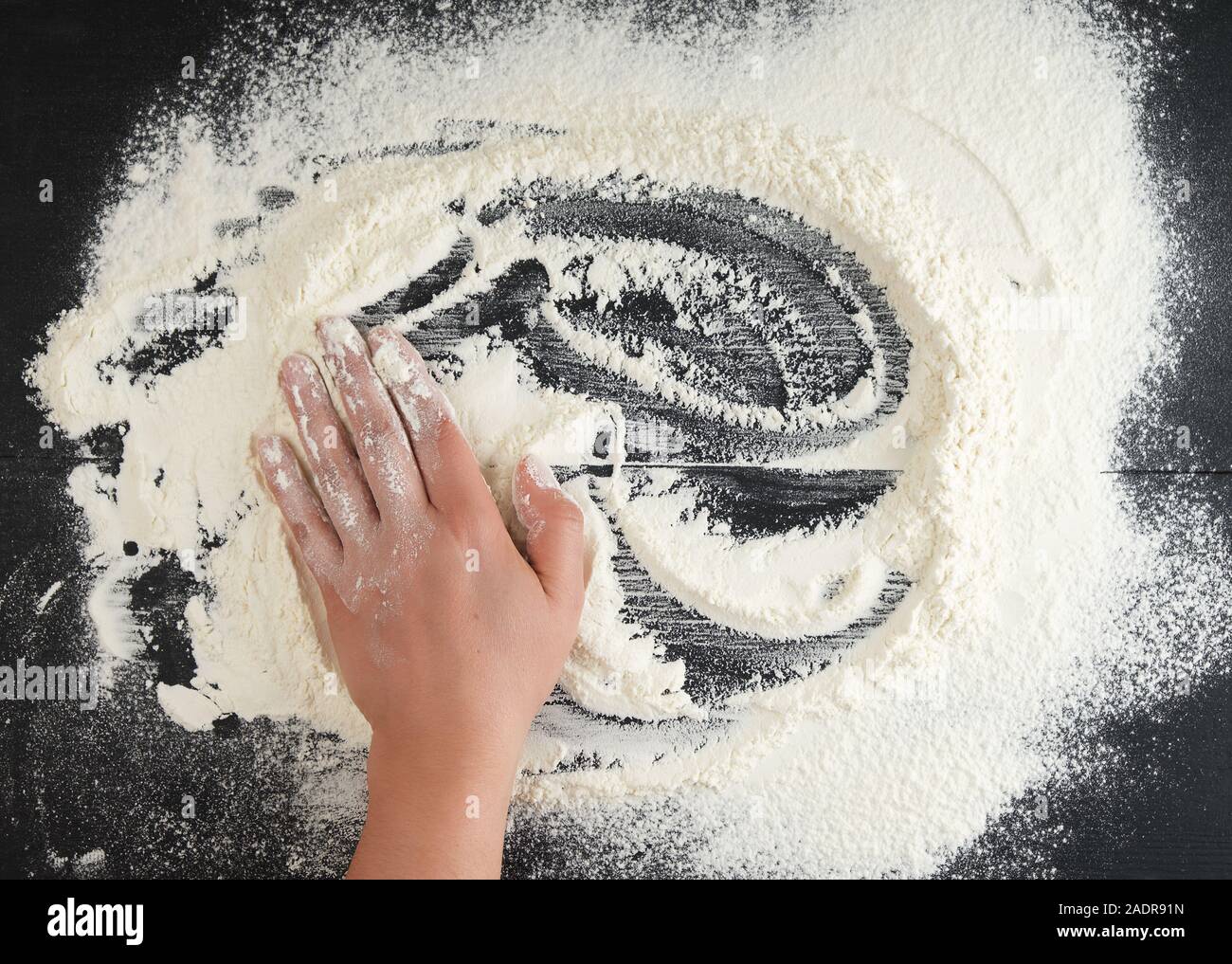 white wheat flour scattered on a black background, product is spread ...
