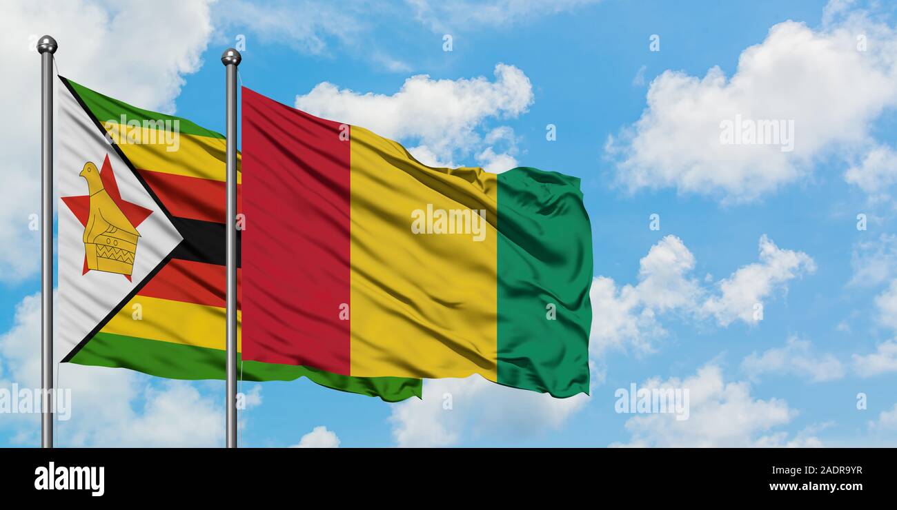 Zimbabwe and Guinea flag waving in the wind against white cloudy blue ...