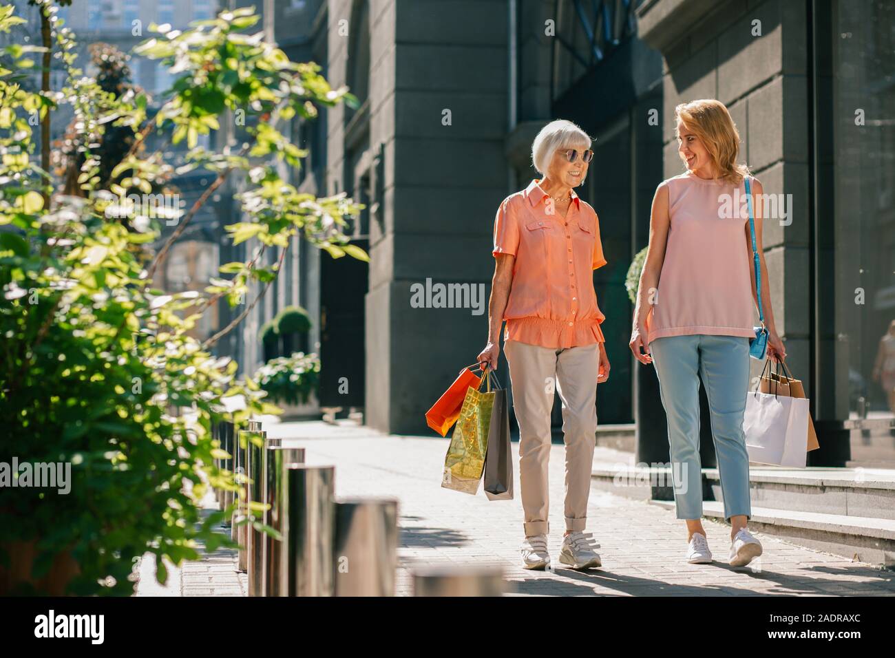 Happy women returning from shop with paper bags in hands Stock Photo ...