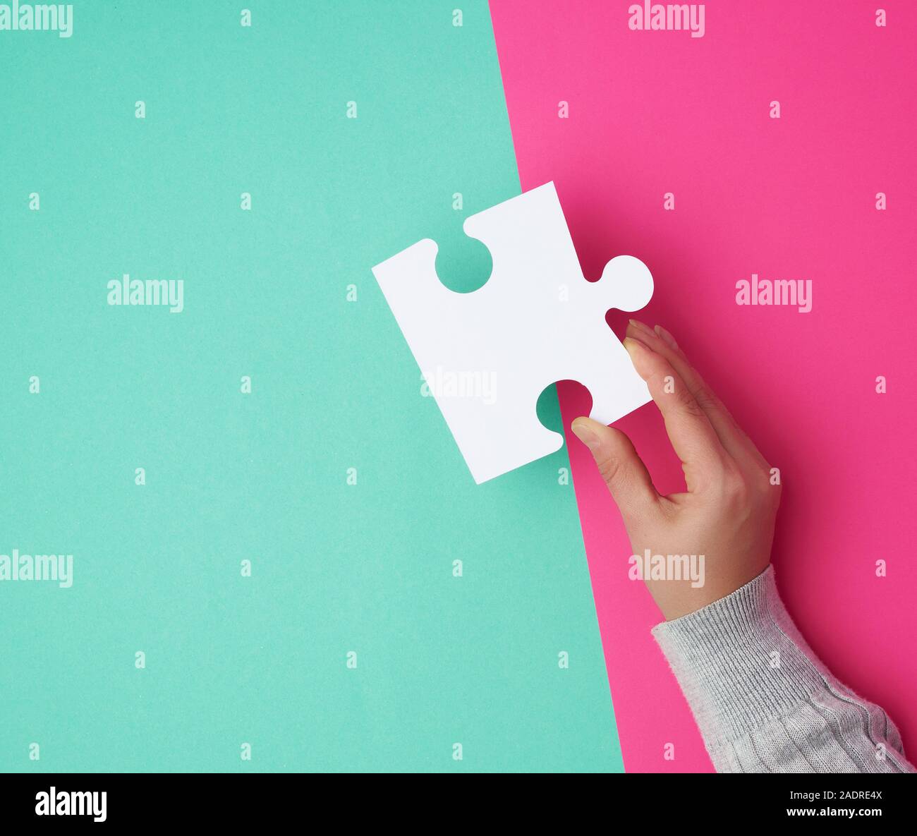 female hand holds a big empty white puzzle over a colorful background ...