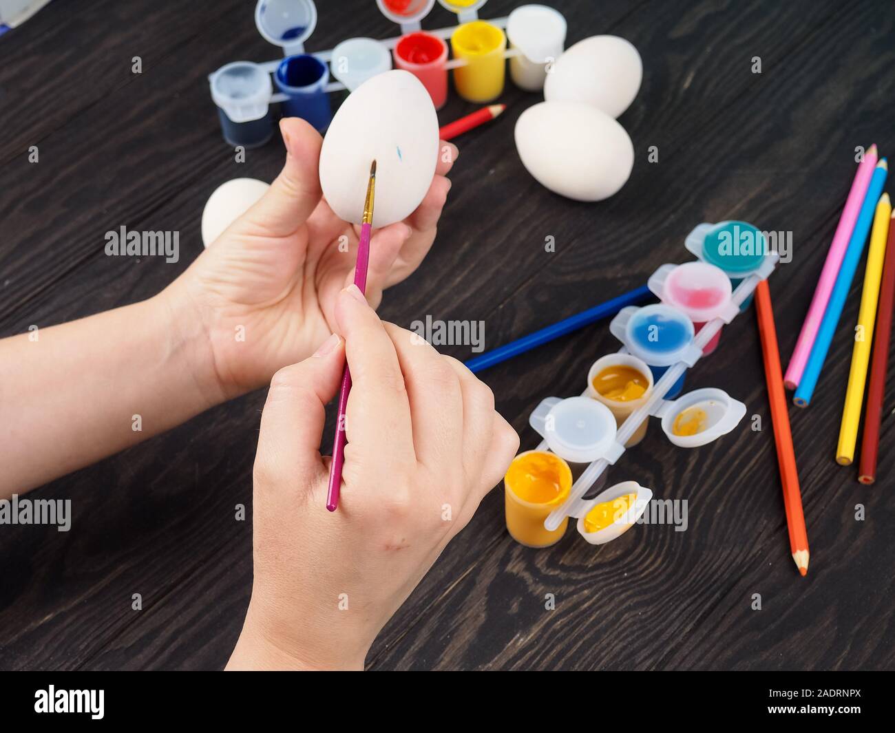Close-up of woman hands painting an easter egg on wooden background ...