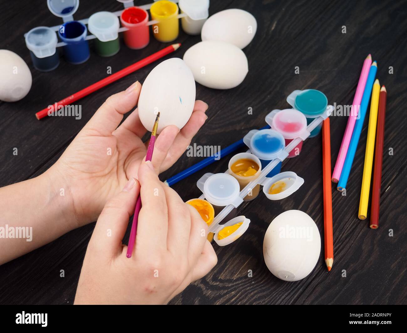 Close-up of woman hands painting an easter egg on wooden background ...