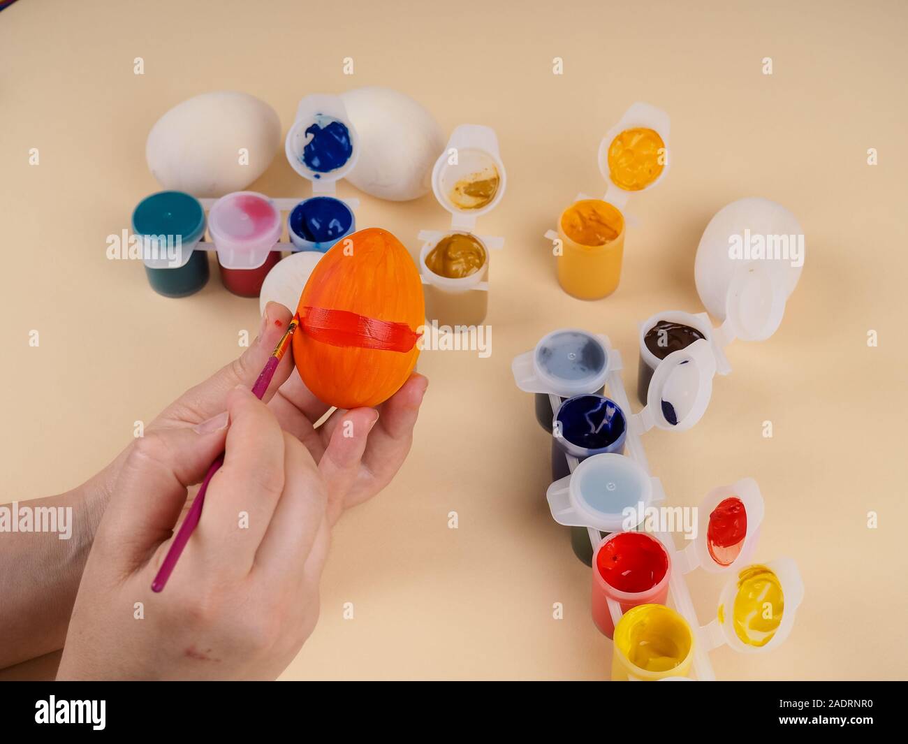 Close-up of woman hands painting an easter egg on wooden background ...