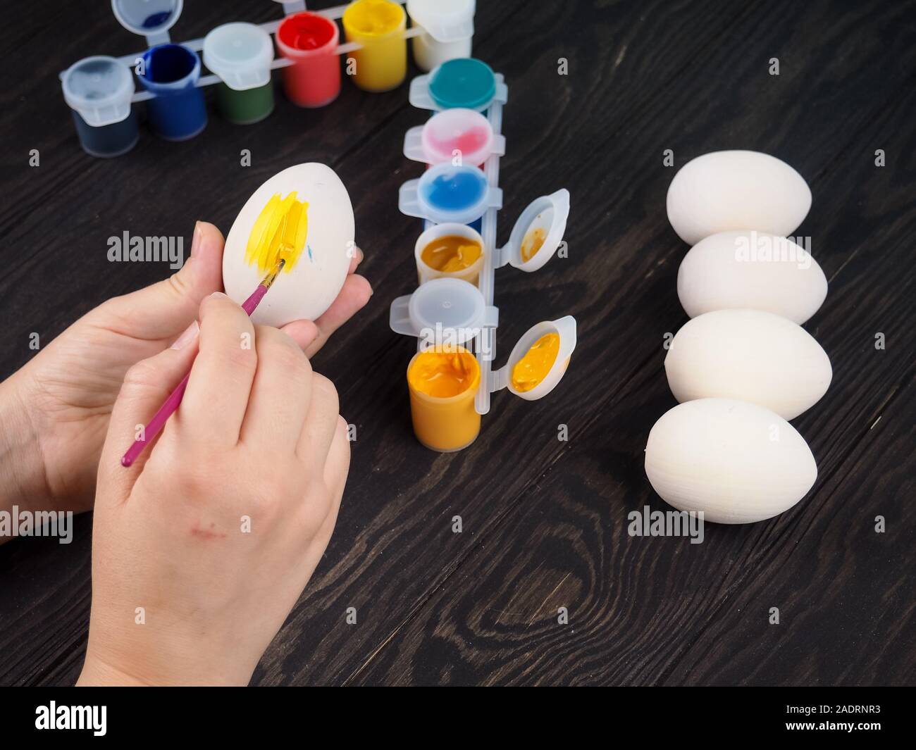 Close-up of woman hands painting an easter egg on wooden background ...