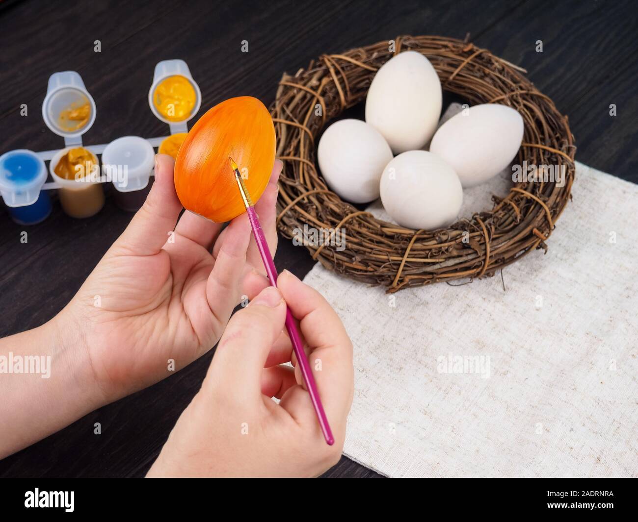 Close-up of woman hands painting an easter egg on wooden background ...
