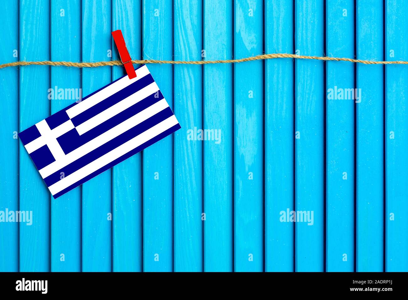Flag of Greece hanging on clothesline attached with wooden clothespins ...