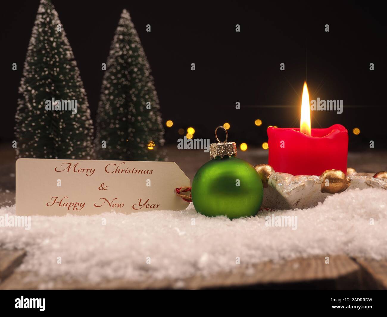 Romantic Christmas background with a candle and a green bauble in snow ...