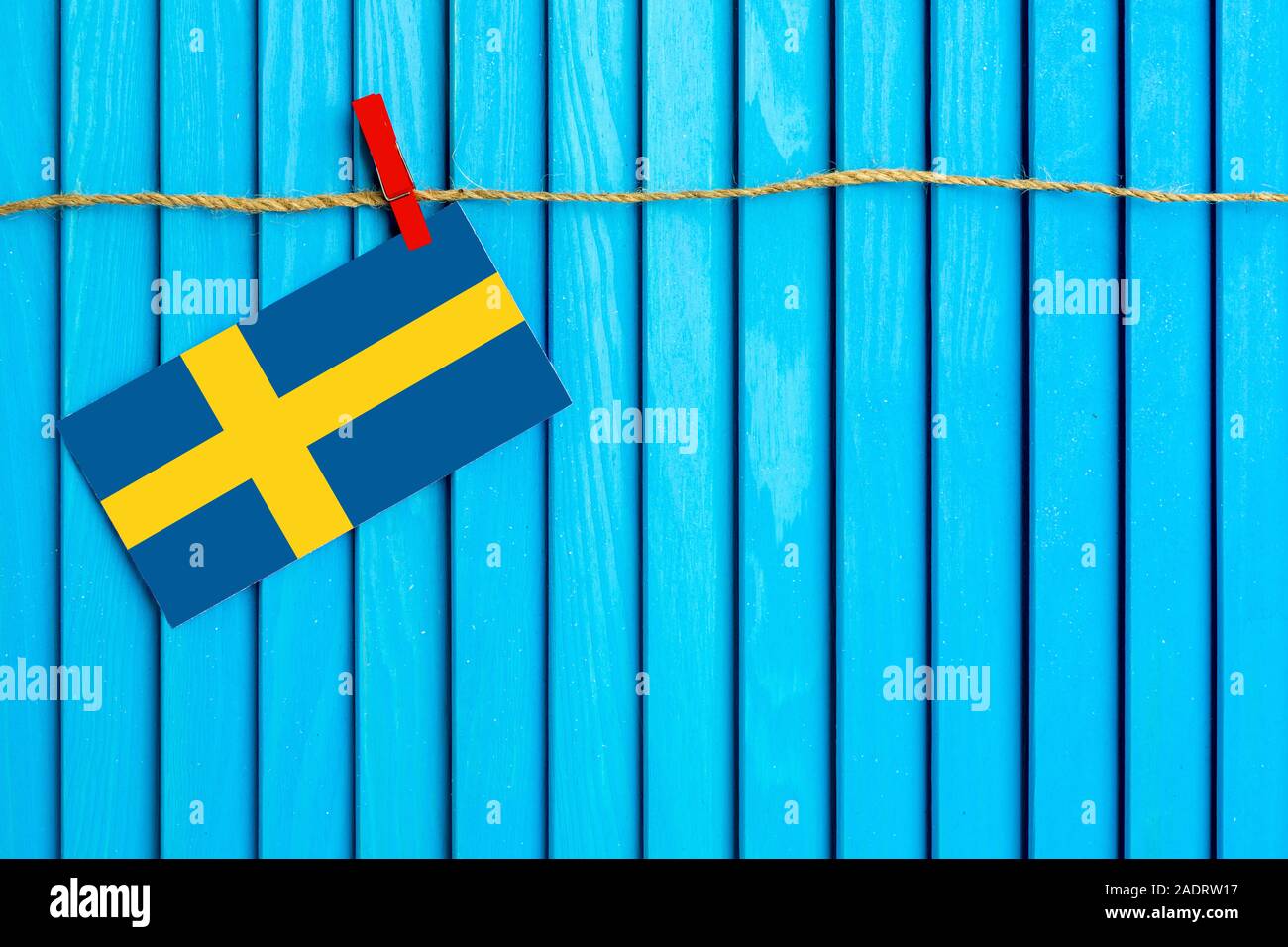 Flag of Sweden hanging on clothesline attached with wooden clothespins ...