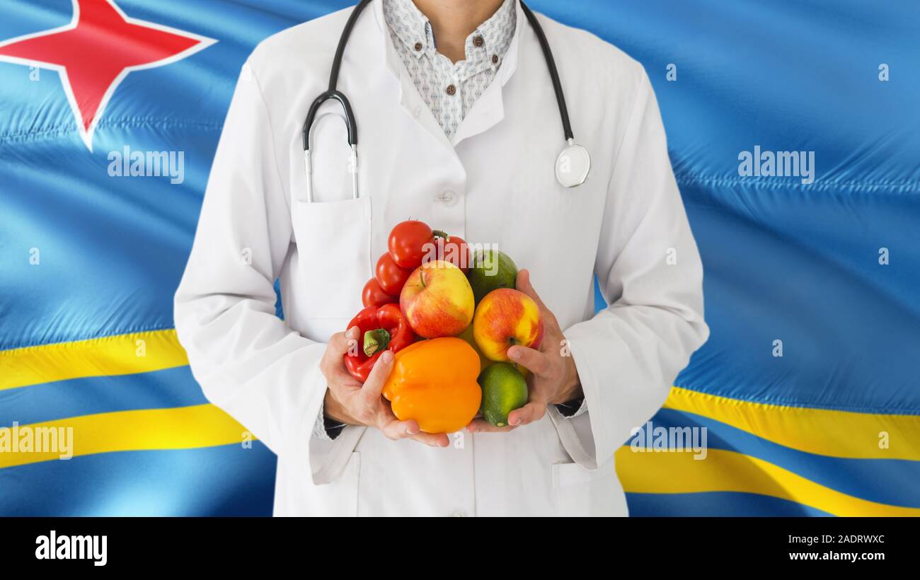 Doctor is holding fruits and vegetables in hands with Aruba flag ...