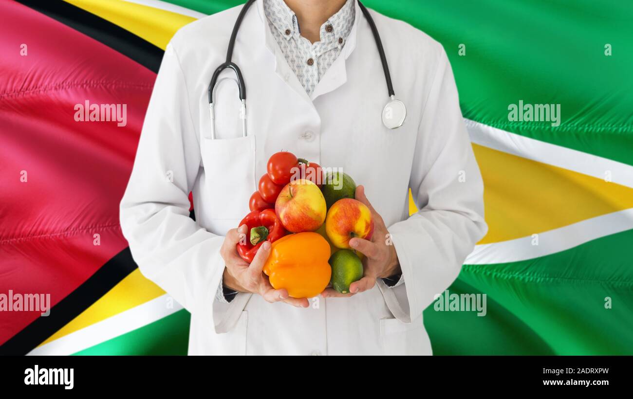 Doctor is holding fruits and vegetables in hands with Guyana flag ...