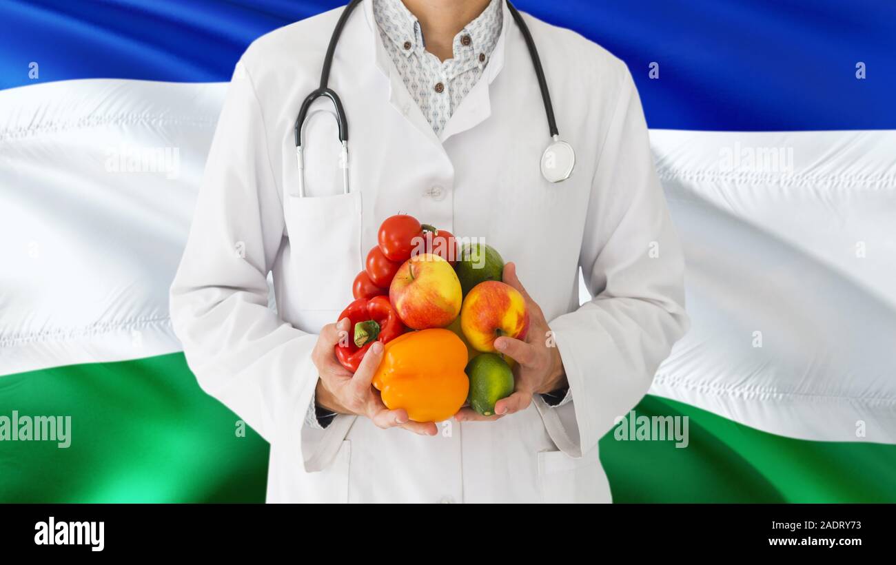 Doctor is holding fruits and vegetables in hands with Lesotho flag ...