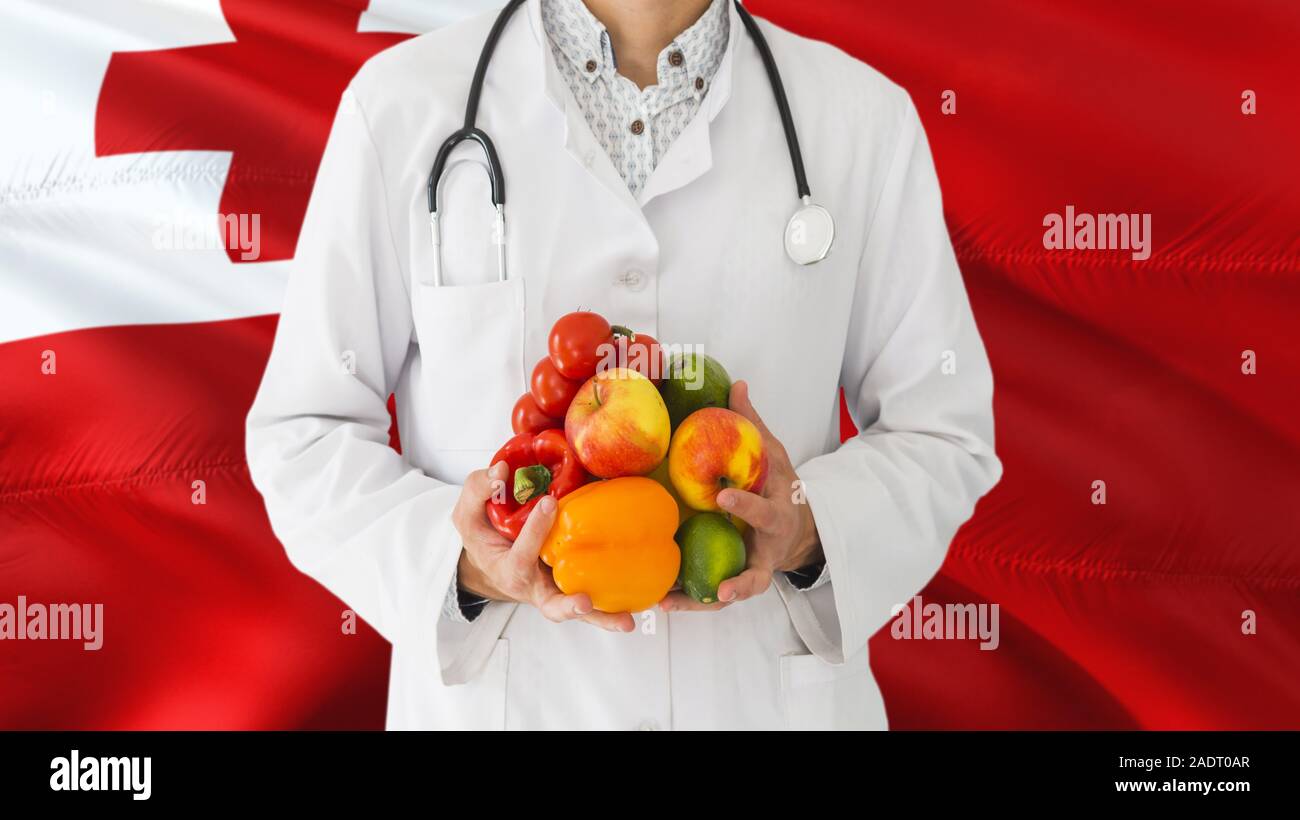 Doctor is holding fruits and vegetables in hands with Tonga flag ...