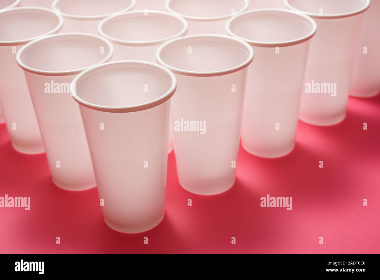 Large group of disposable plastic cups on a pink table Stock Photo - Alamy