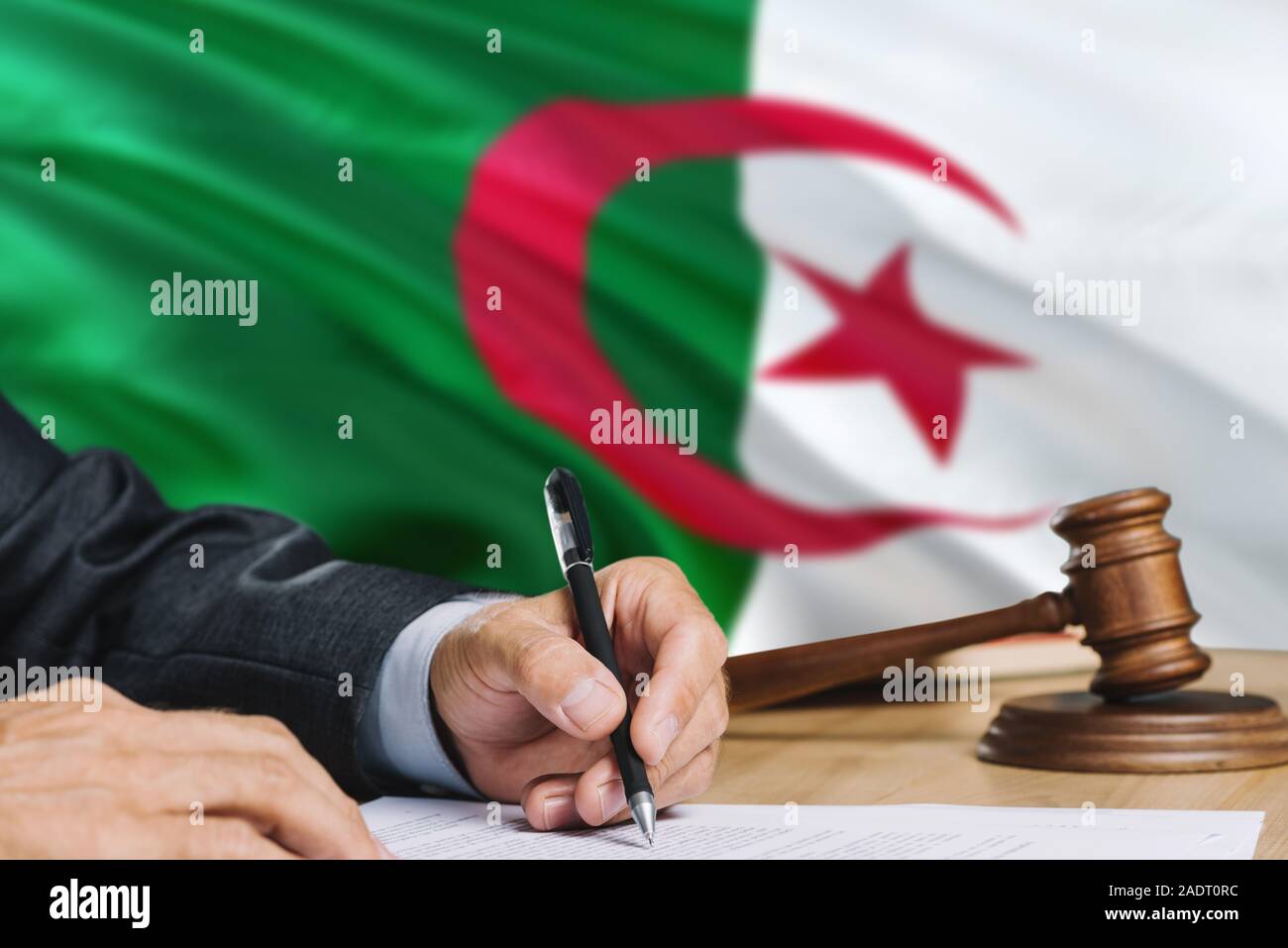 Judge writing on paper in courtroom with Algeria flag background ...