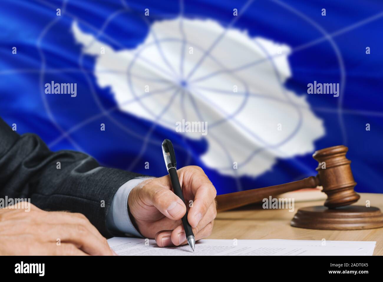 Judge writing on paper in courtroom with Antarctica flag background ...