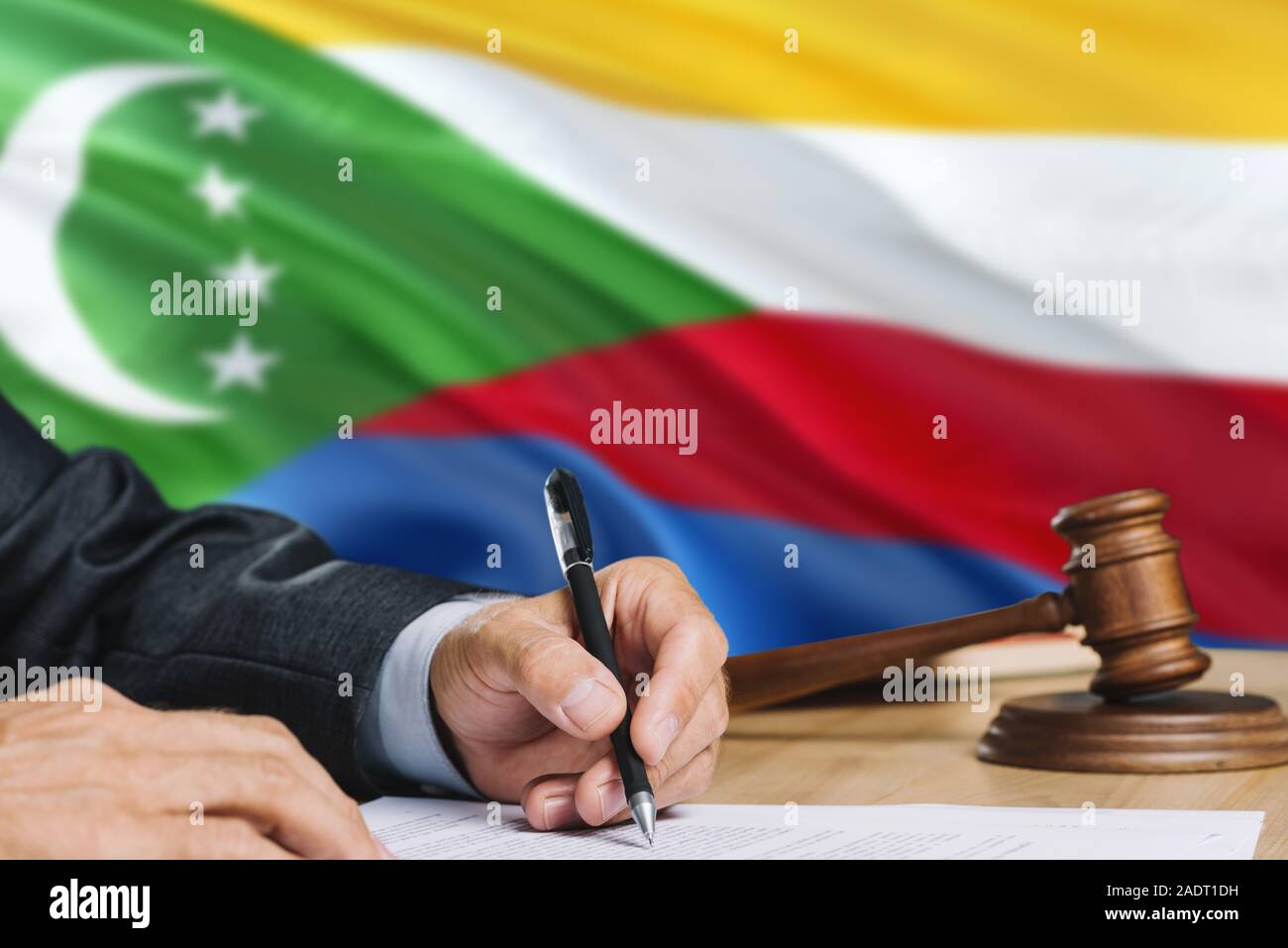 Judge writing on paper in courtroom with Comoros flag background ...