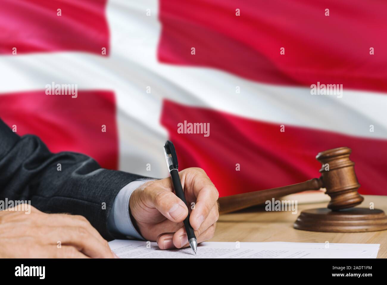 Judge writing on paper in courtroom with Denmark flag background ...