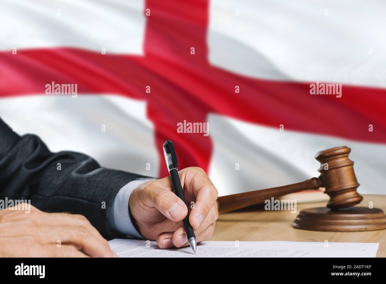 Judge writing on paper in courtroom with England flag background ...