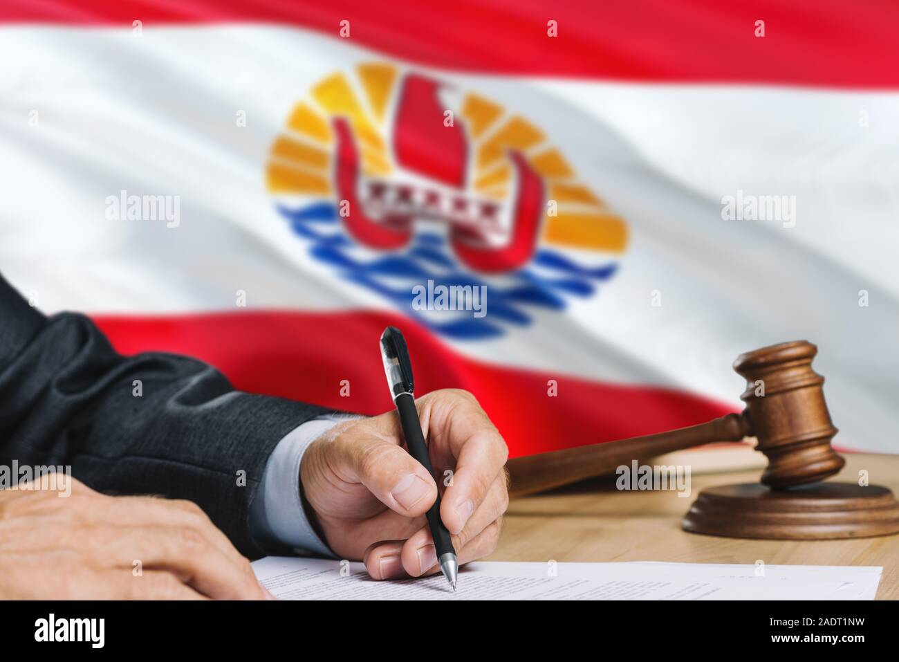 Judge writing on paper in courtroom with French Polynesia flag ...