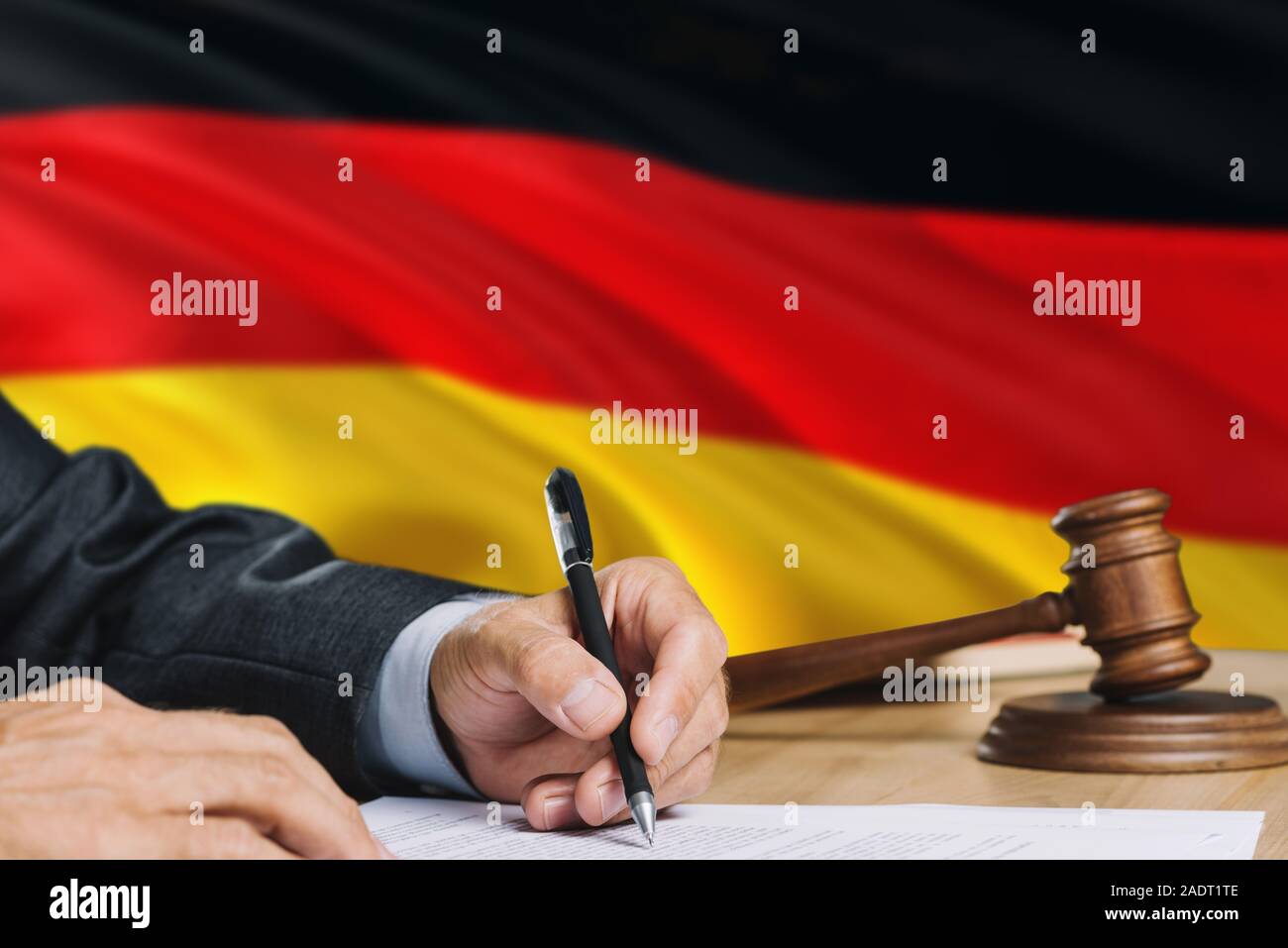 Judge writing on paper in courtroom with Germany flag background ...