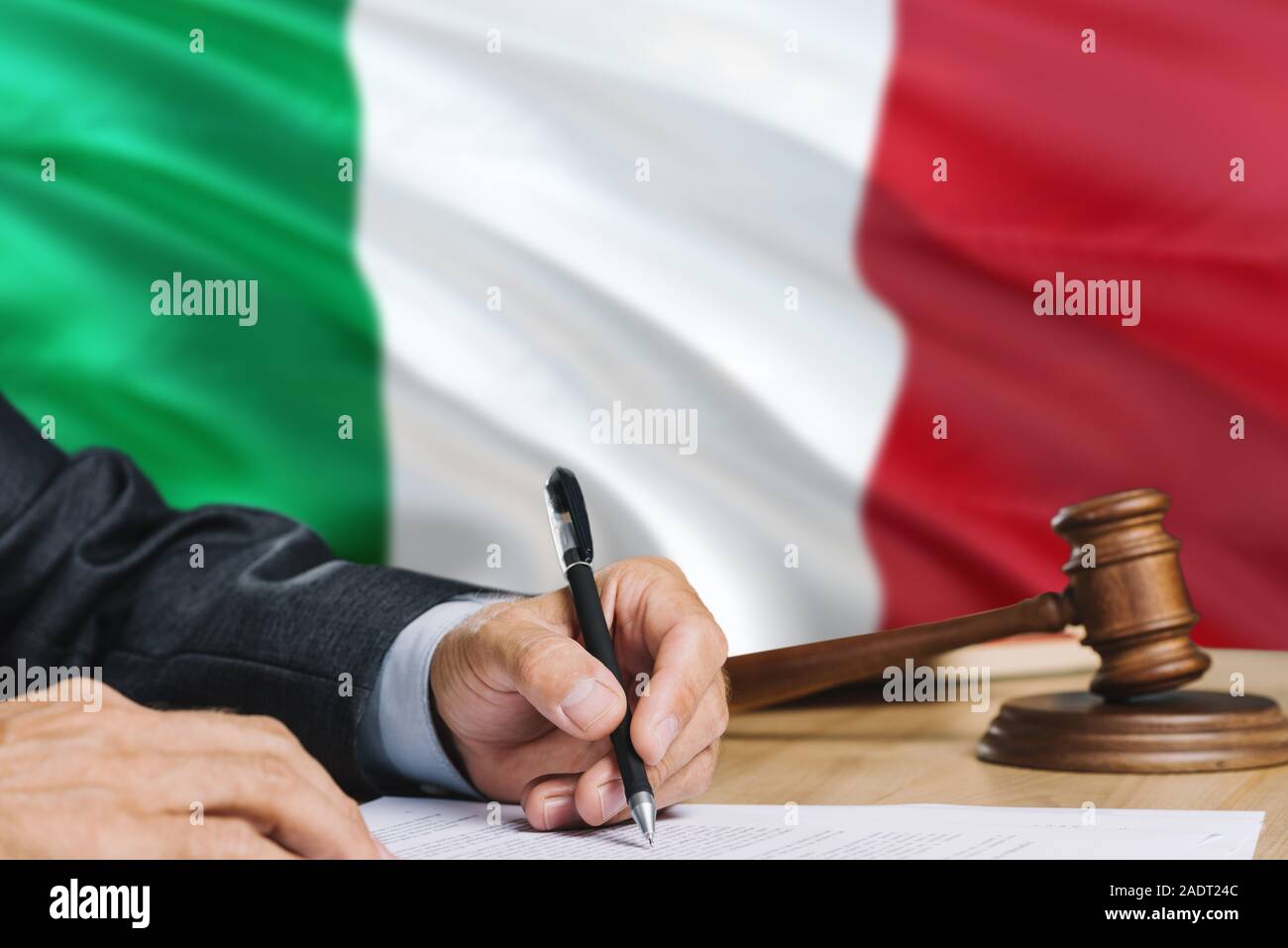 Judge writing on paper in courtroom with Italy flag background. Wooden ...