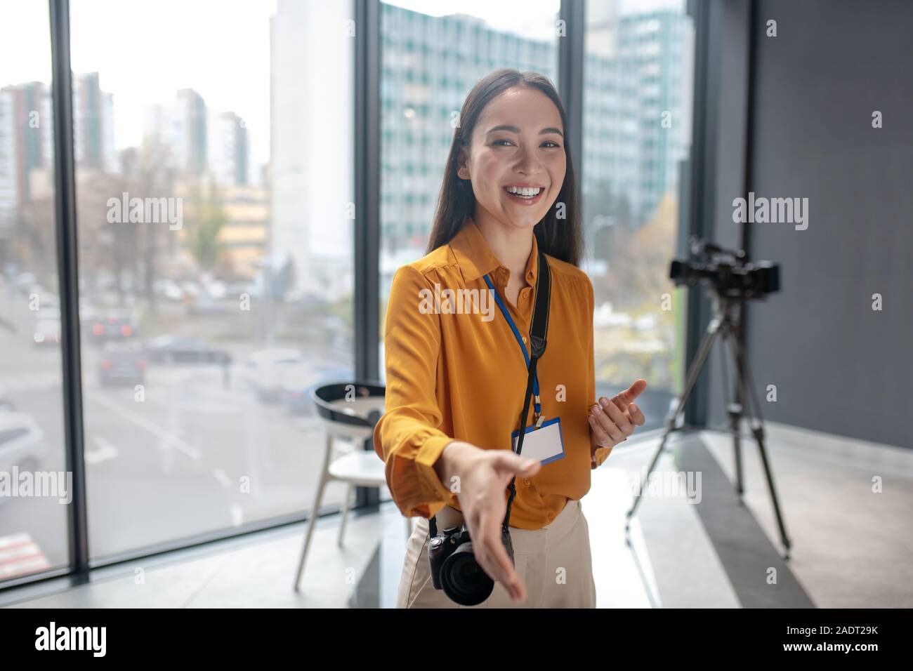 Dark-haired young cute reporter with camera smiling positively Stock ...