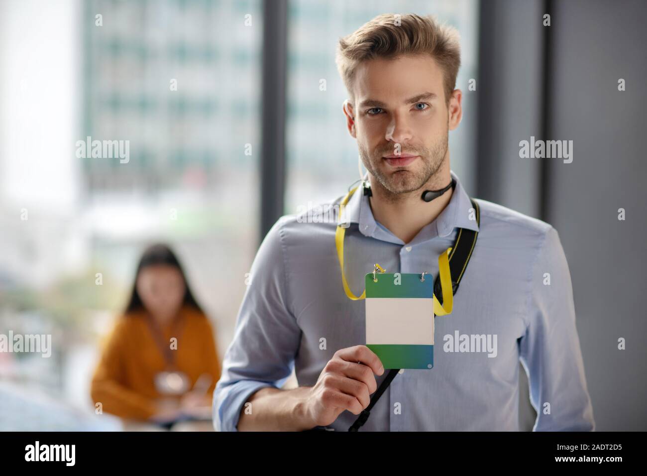 Young man in a blue shirt showing his badge Stock Photo - Alamy