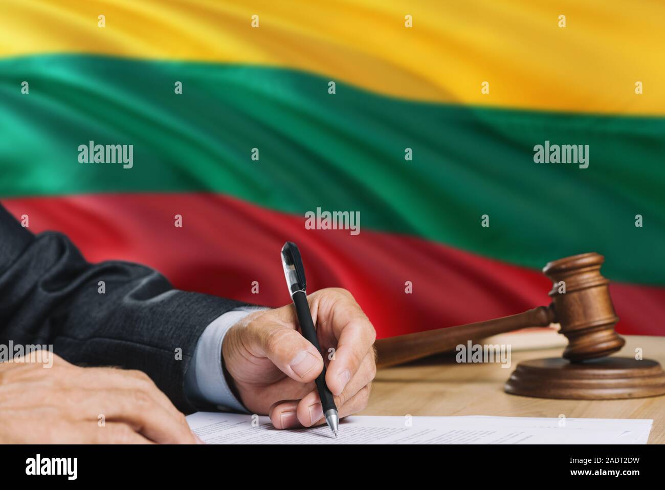 Judge writing on paper in courtroom with Lithuania flag background ...