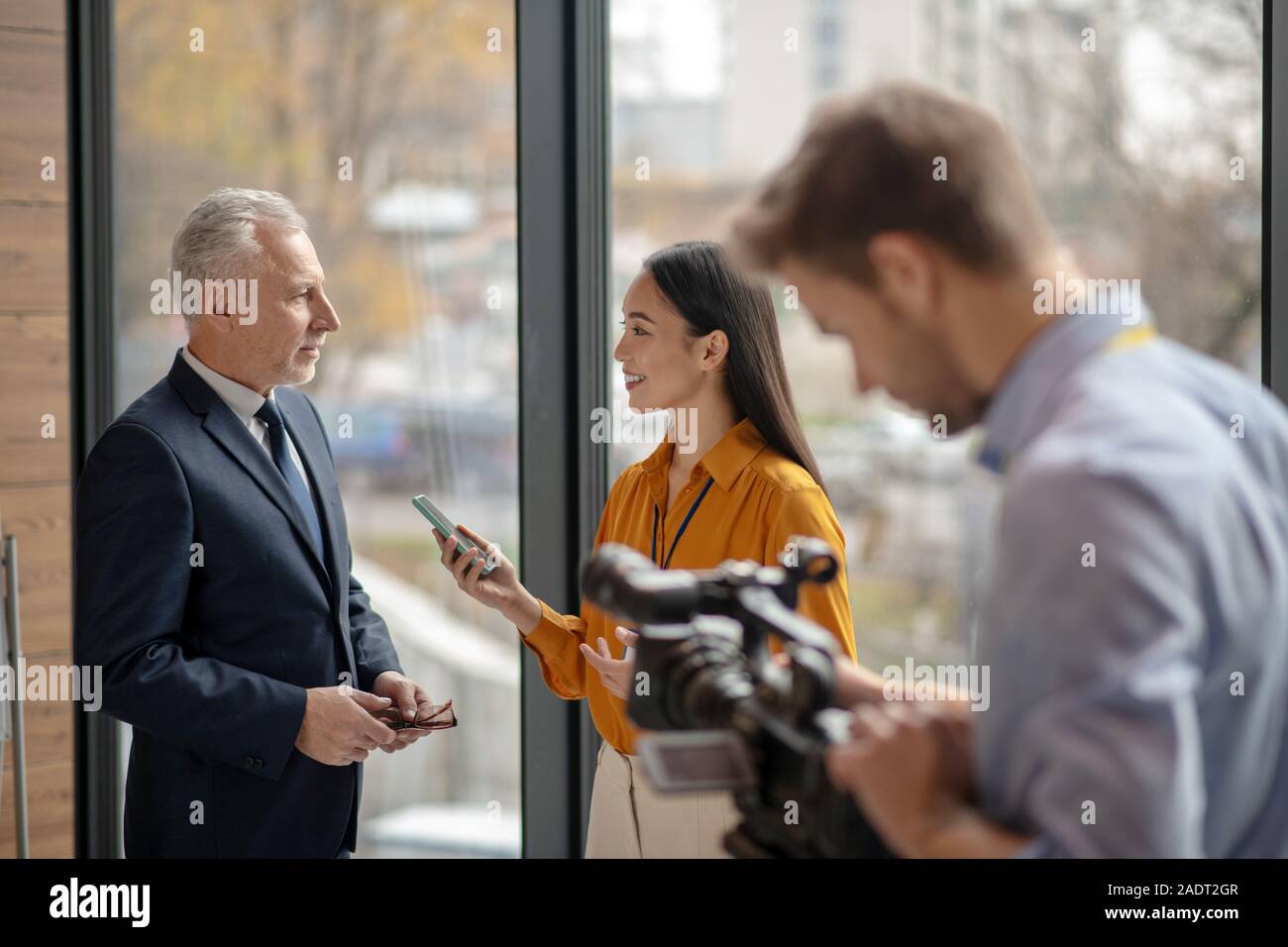 Asian female reporter holding a microphone and smiling Stock Photo - Alamy