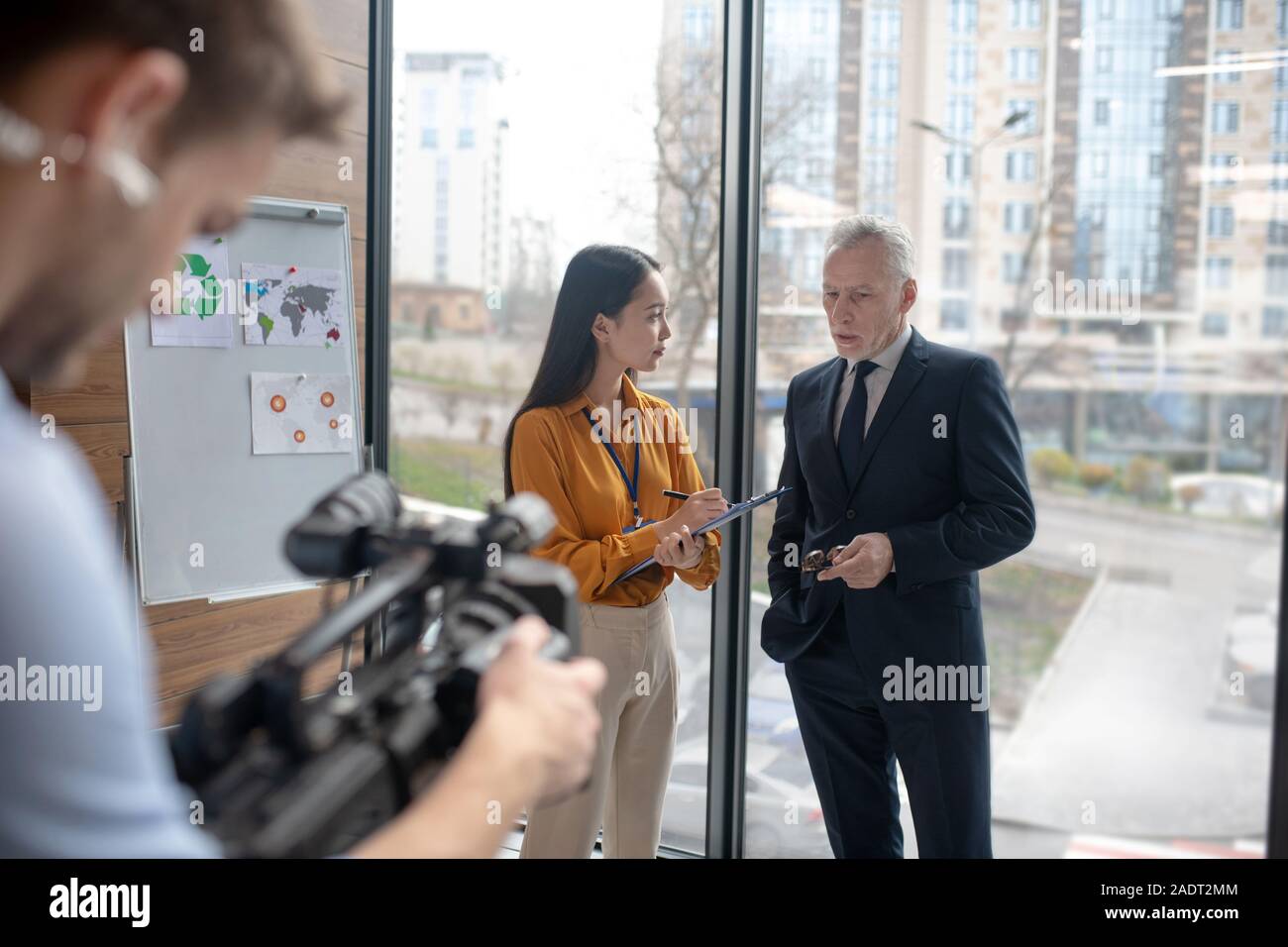 Young asian reporter standing next to grey-haired man Stock Photo - Alamy
