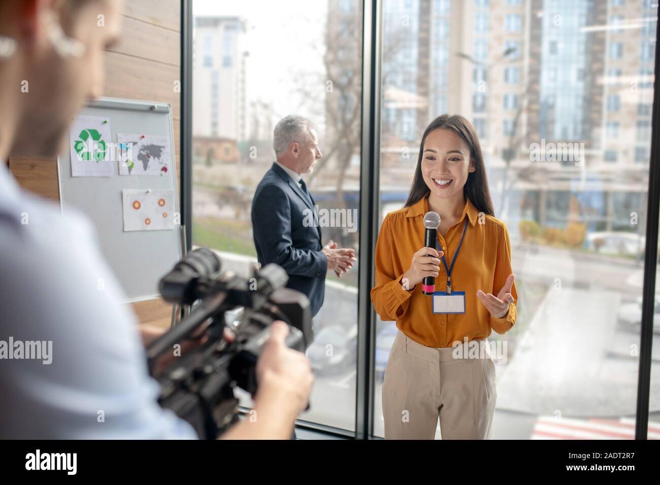Dark-haired female reporter smiling to the camera Stock Photo - Alamy