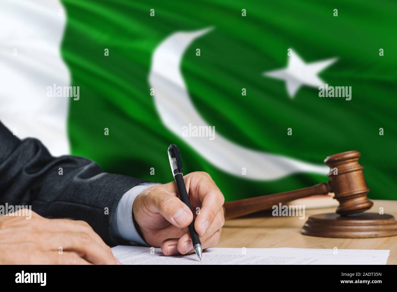 Judge writing on paper in courtroom with Pakistan flag background ...