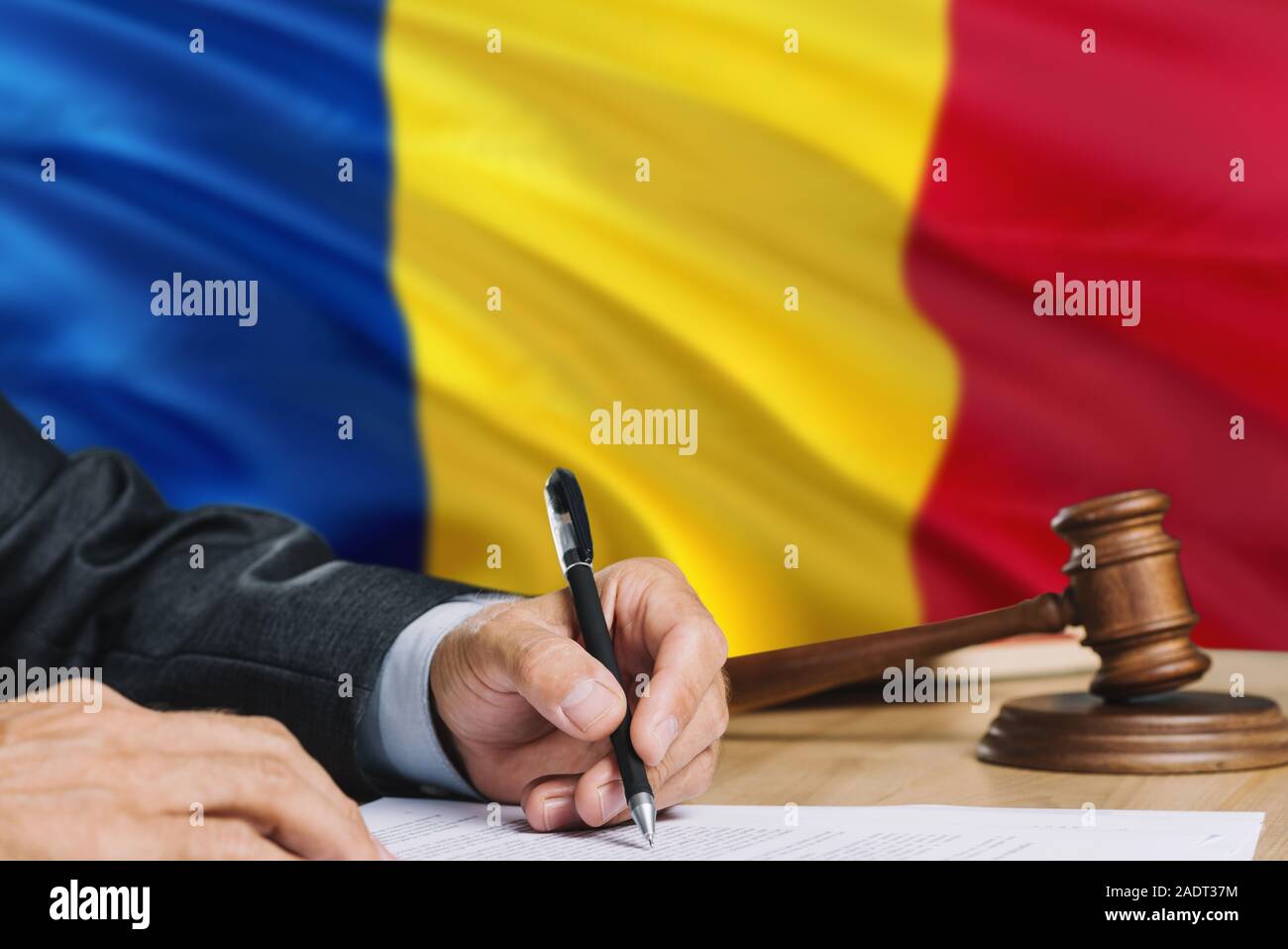 Judge writing on paper in courtroom with Romania flag background ...