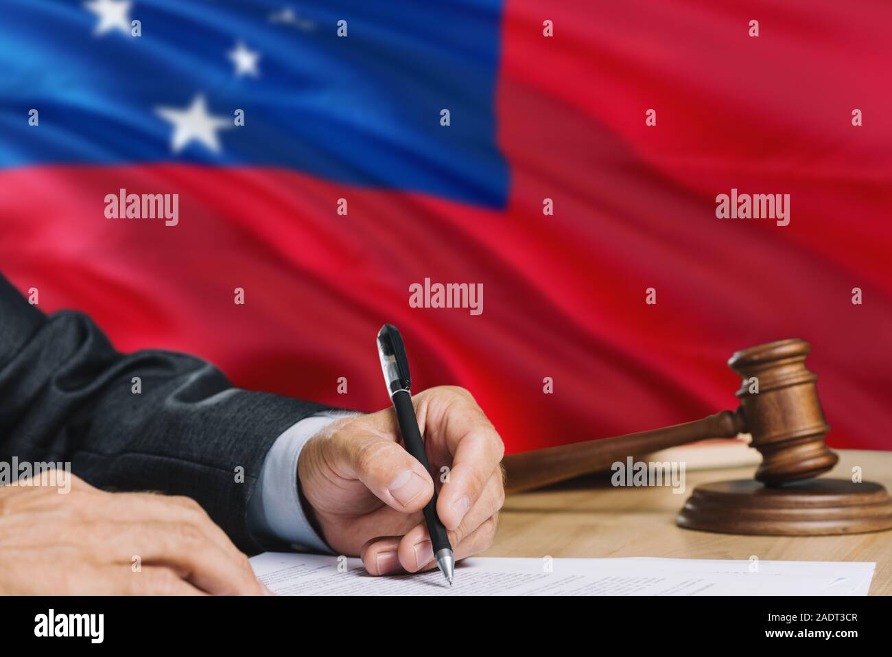 Judge writing on paper in courtroom with Samoa flag background. Wooden ...